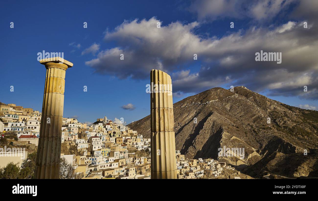 Ancient columns stand in front of a village that blends into an ...