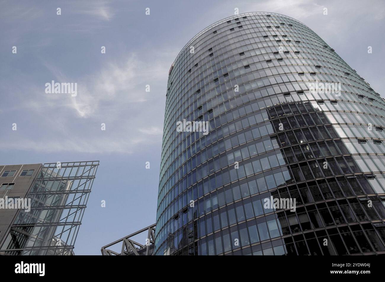 Modern round skyscraper with glass facade in front of a cloudy sky ...