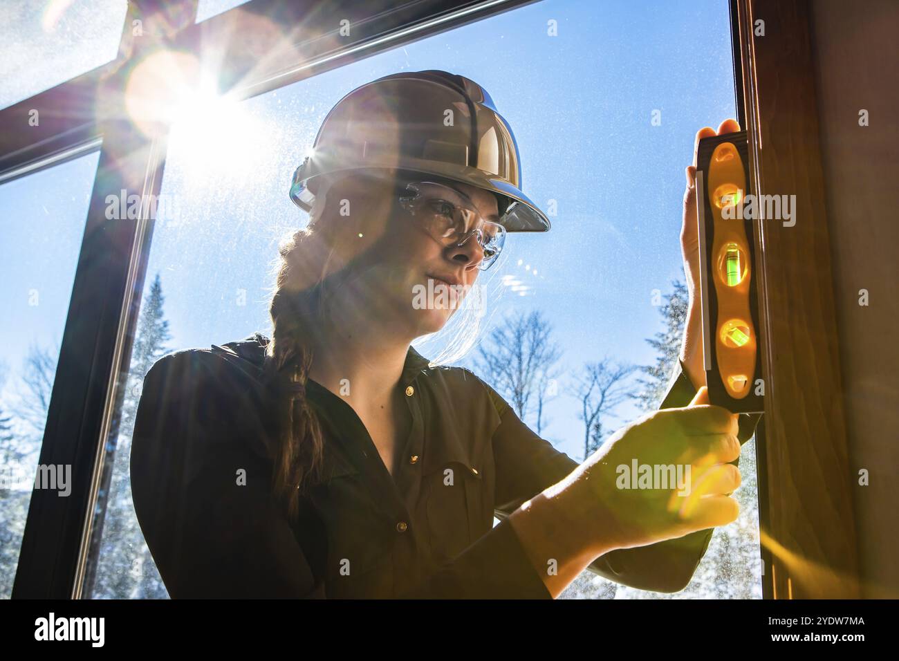 Close up on worker woman uses spirit level on vertical surface next to ...