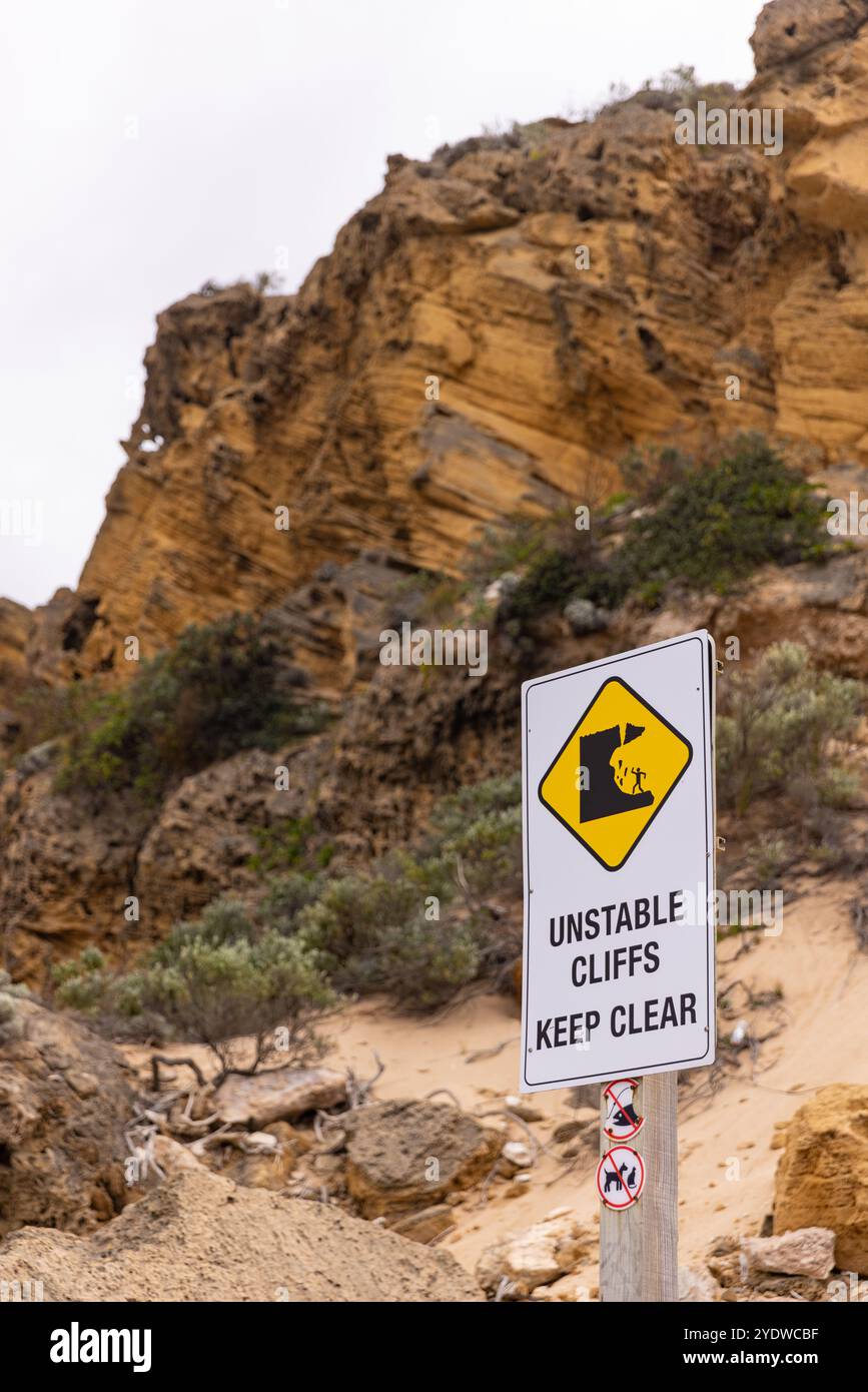 Warning sign for unstable sea cliffs near rugged rocky landscape Stock ...