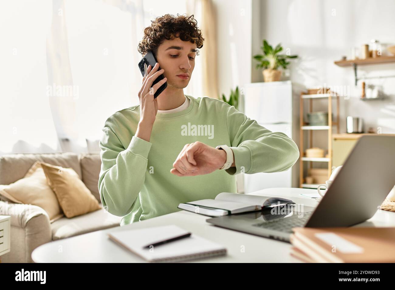 A handsome young man in a modern space manages tasks on his laptop ...