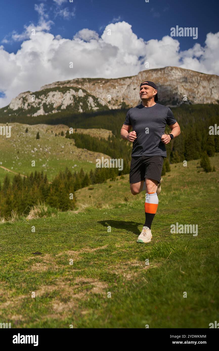Trail runner man running on a meadow below the high mountain range ...