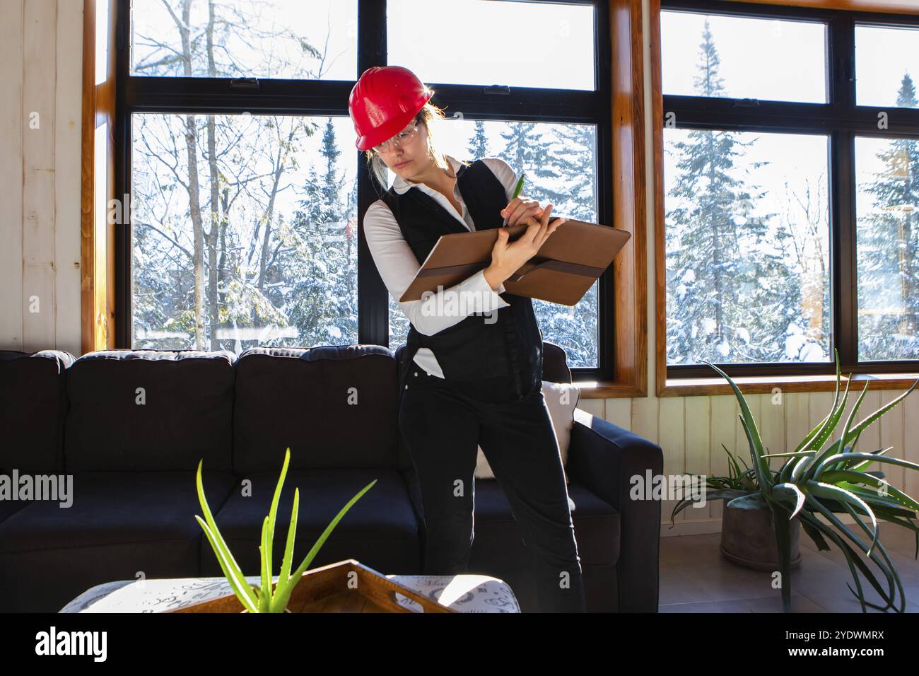 Home inspector woman wearing red hard hat takes professional notes on ...