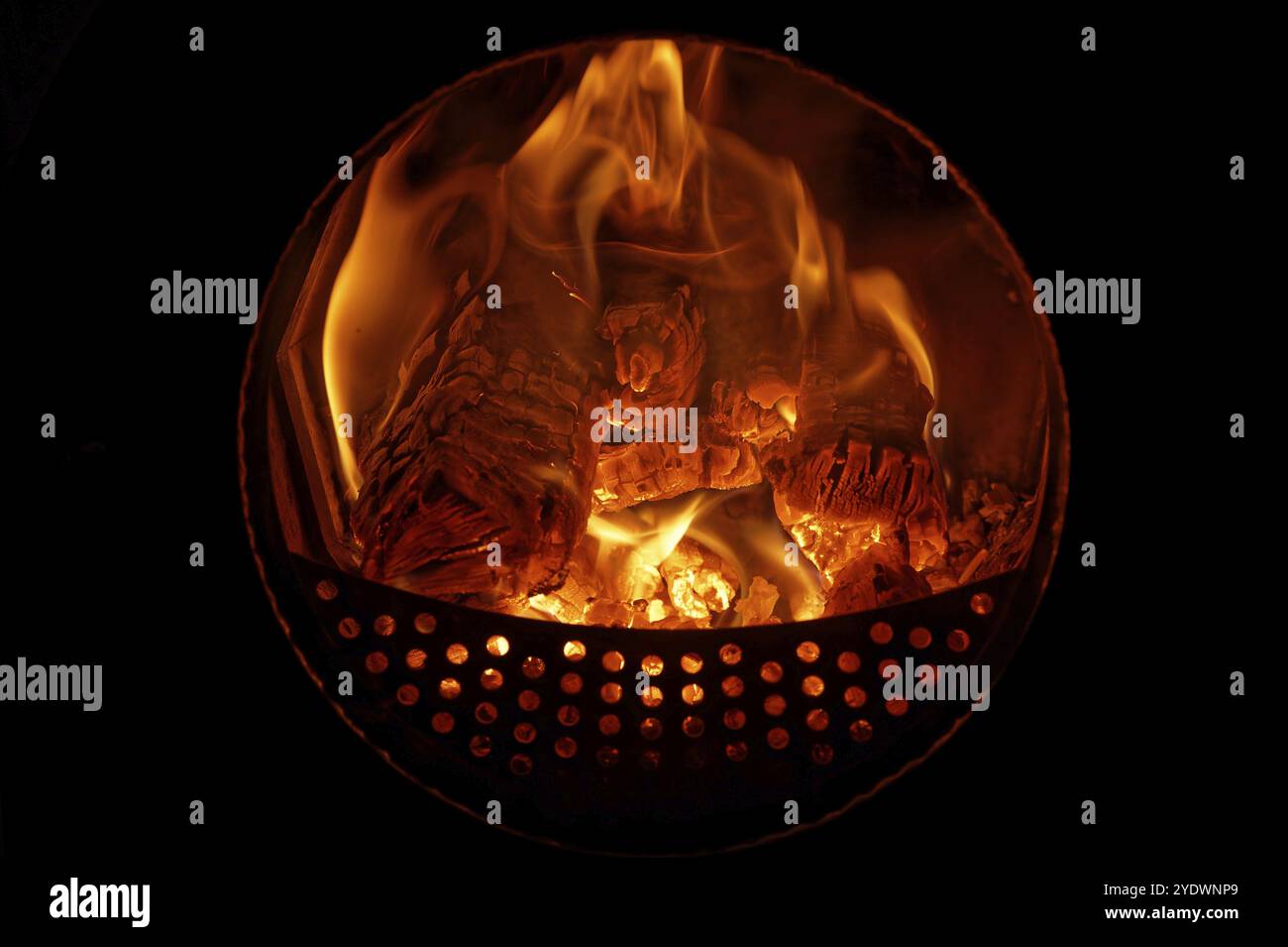 Logs burn and glow in a wood-burning stove with a round glass window ...