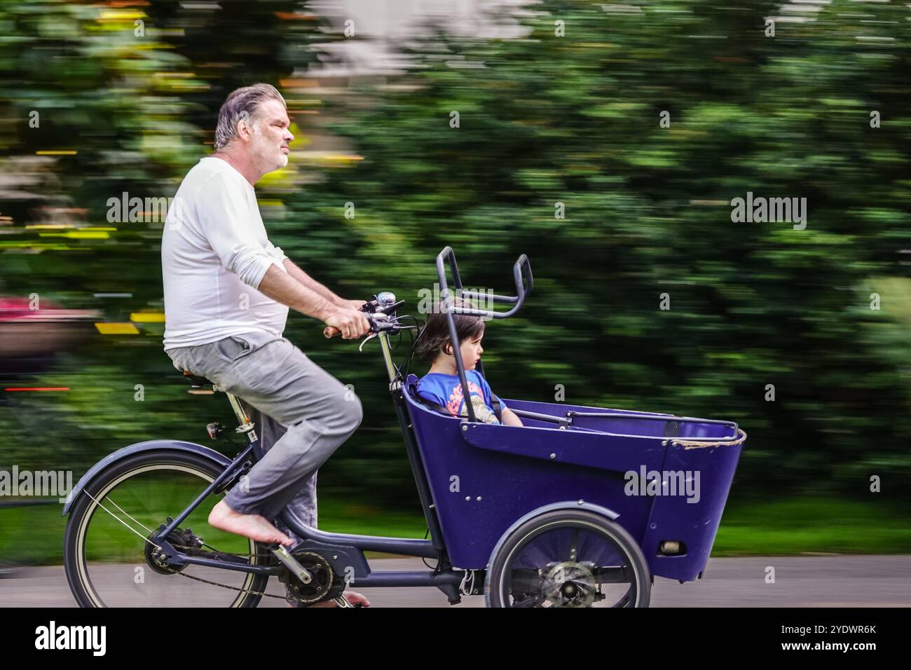 An electric cargo bike transports a man and child along Quai Gustave-Ador bicycle path in Geneva ...