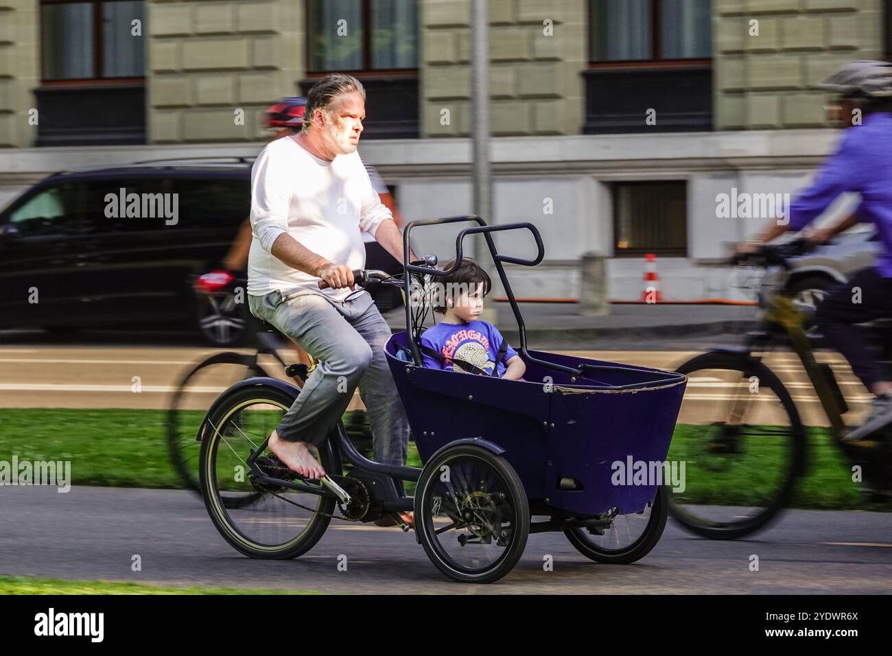 An electric cargo bike transports a man and child along Quai Gustave-Ador bicycle path in Geneva ...