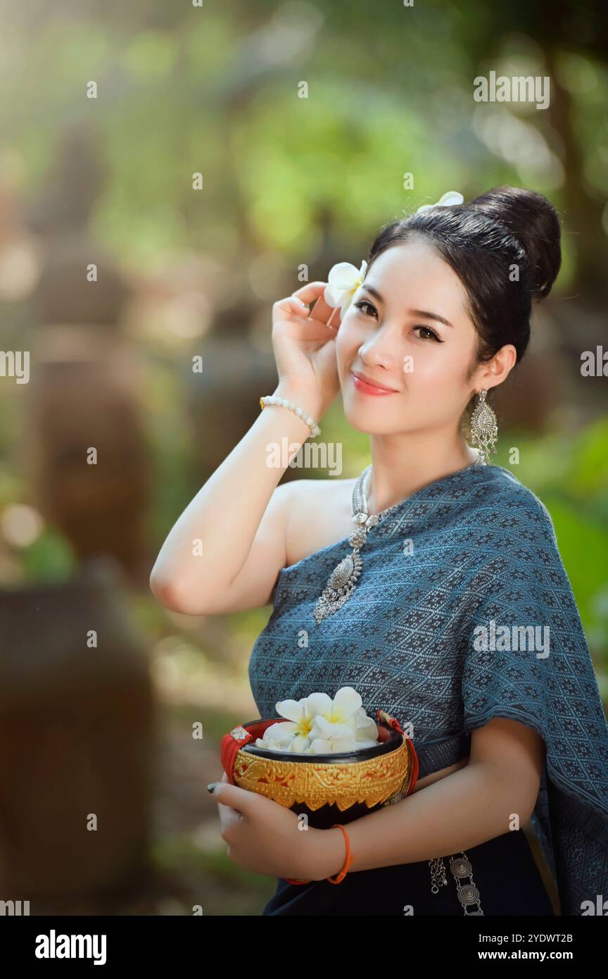 Smiling young woman in traditional Lao clothing holding a bowl of ...