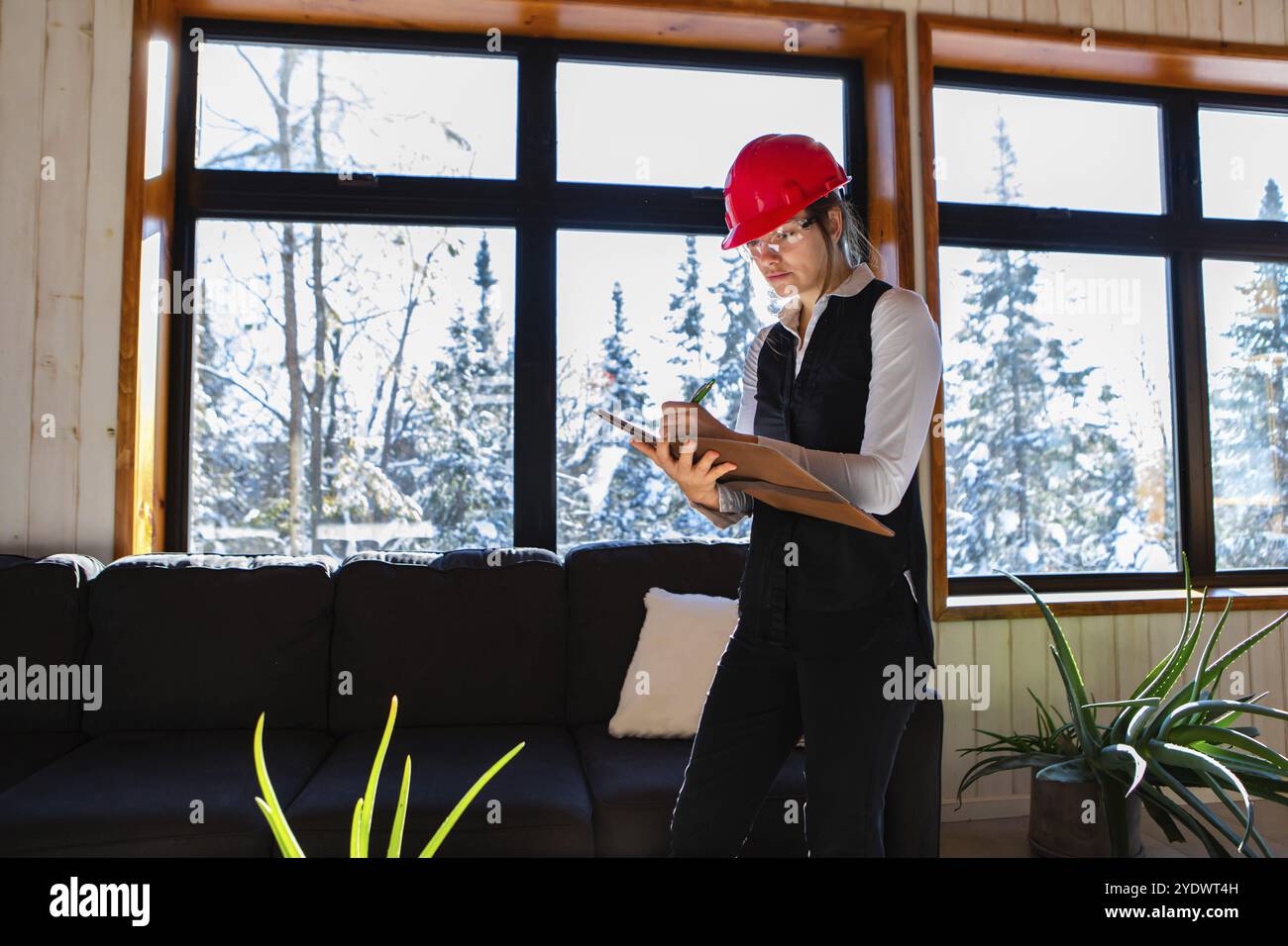 Home inspector woman wearing red hard hat takes professional notes on ...