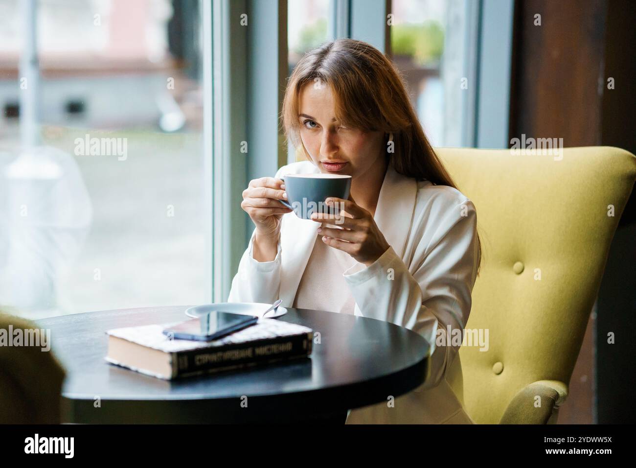 Elegant Woman Enjoying Coffee in a Chic Cafe Setting Stock Photo - Alamy