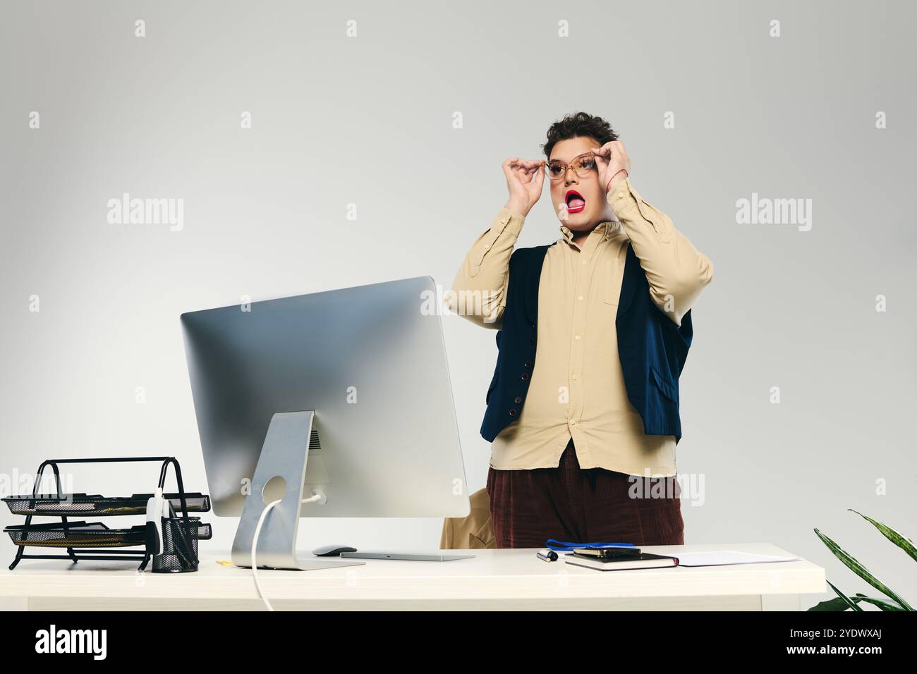 A queer person reacts with shock while working at a sleek desk ...