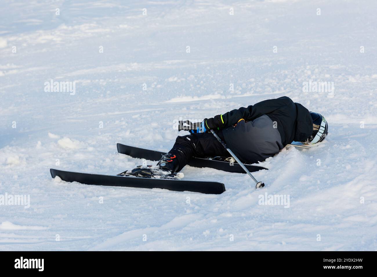 Little teen boy kid in black suit lying on snow after ski downhill ...