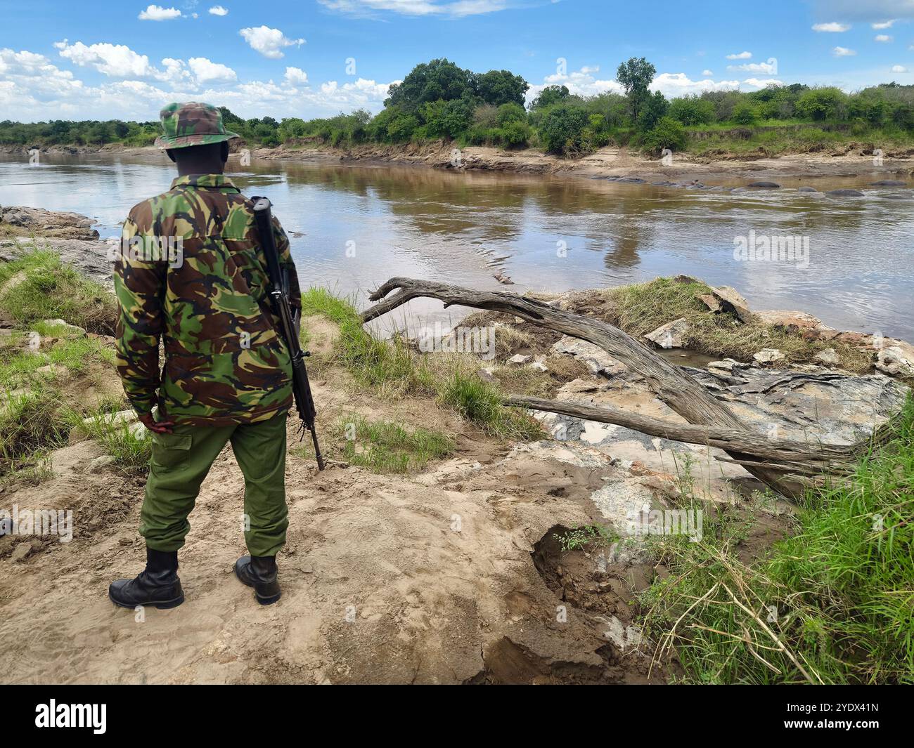 African soldier are walking along the river bank, tracking wild animals ...