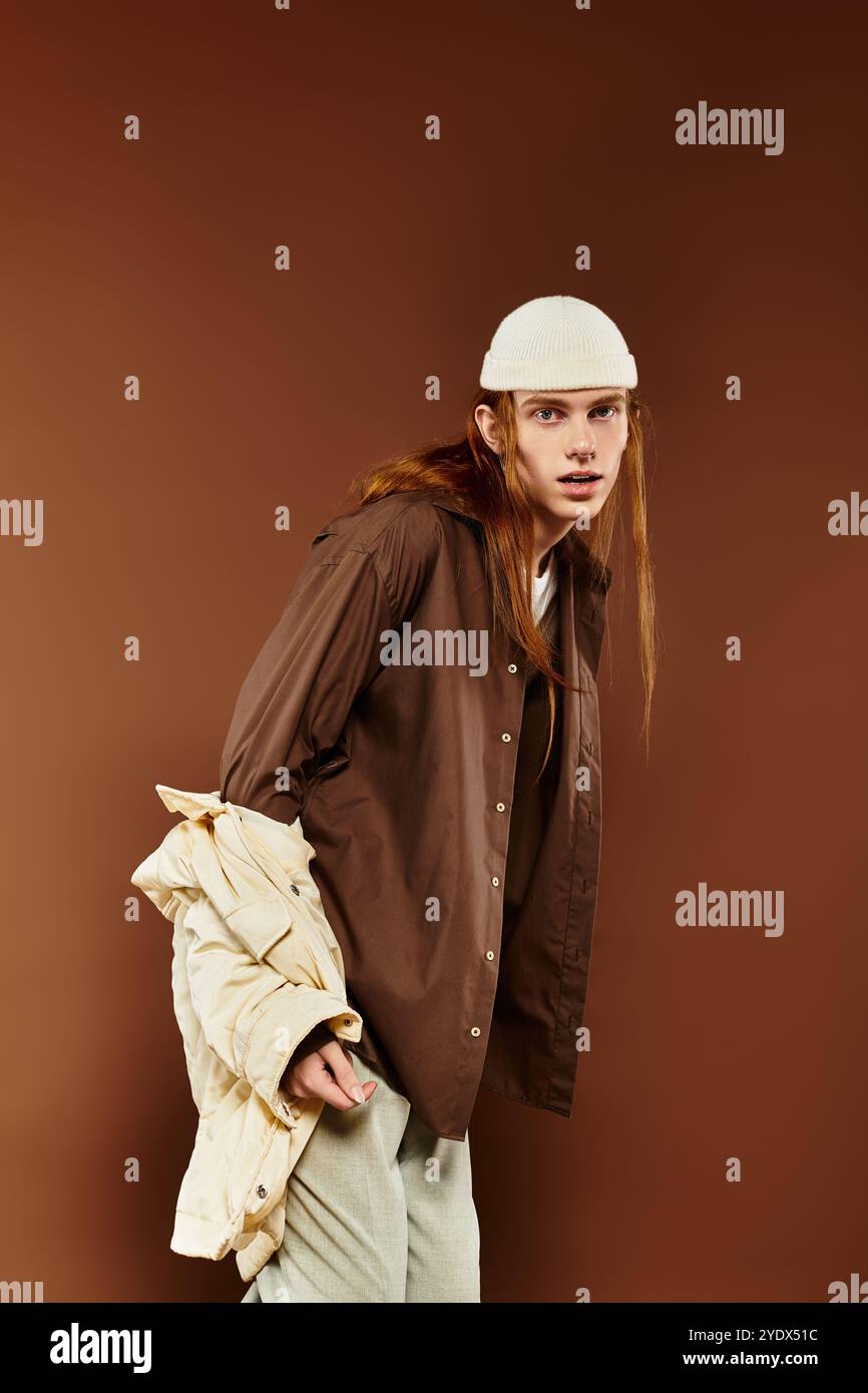 A young boy with vibrant red hair models trendy clothing against a warm ...