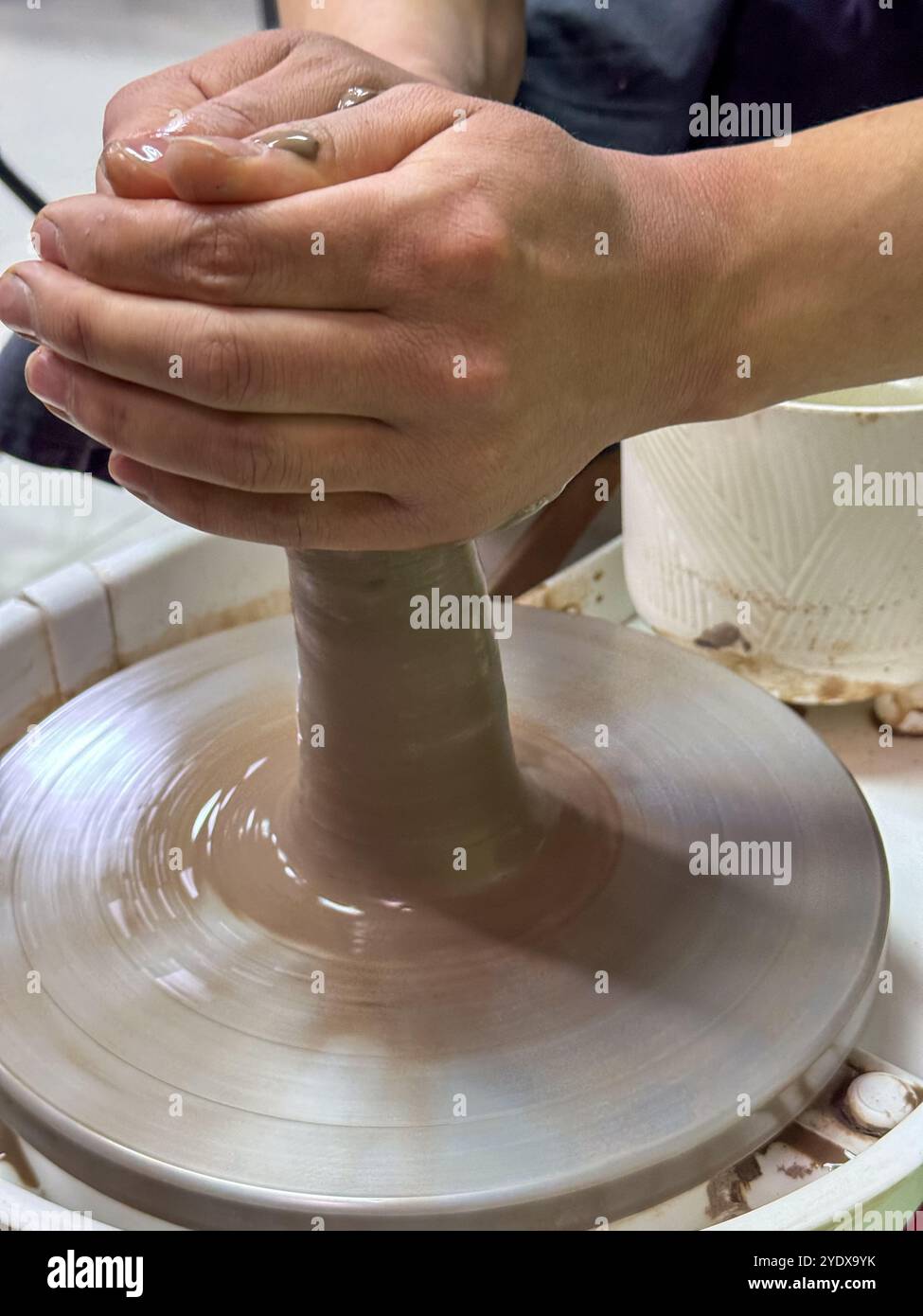 Handcrafting ceramics on a pottery wheel. Male hands shaping a clay ...