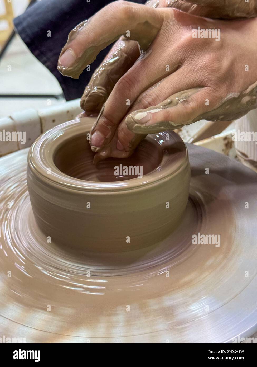 Handcrafting ceramics on a pottery wheel. Male hands shaping a clay ...
