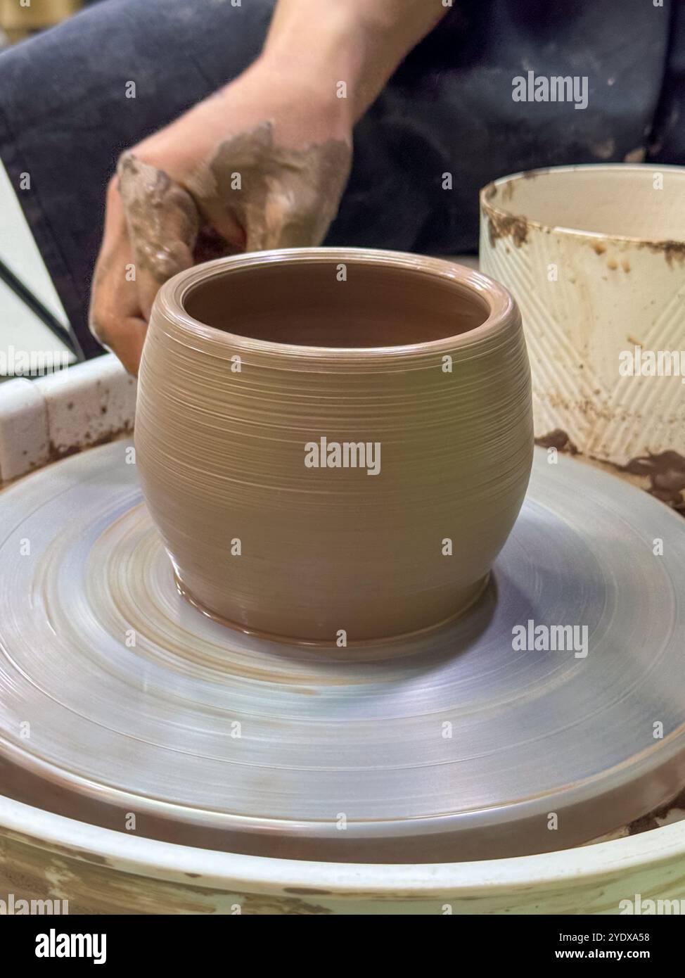 Handcrafting ceramics on a pottery wheel. Male hands shaping a clay ...