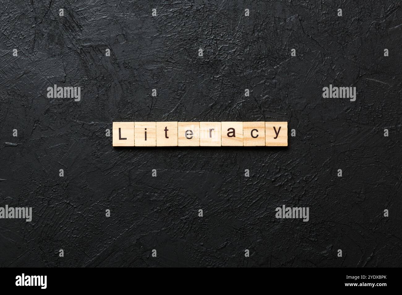 LITERACY word written on wood block. LITERACY text on cement table for ...