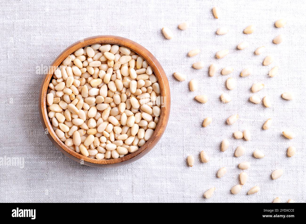 Pine nuts in a wooden bowl on linen fabric. Also known as pinon, pinoli ...