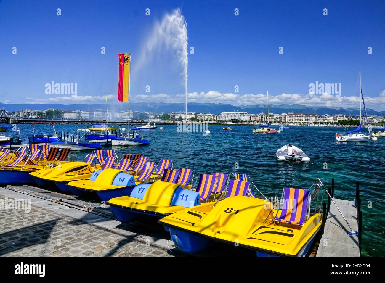 Pedal boats line up along Lake Geneva with the landmark Jet d’Eau or La ...