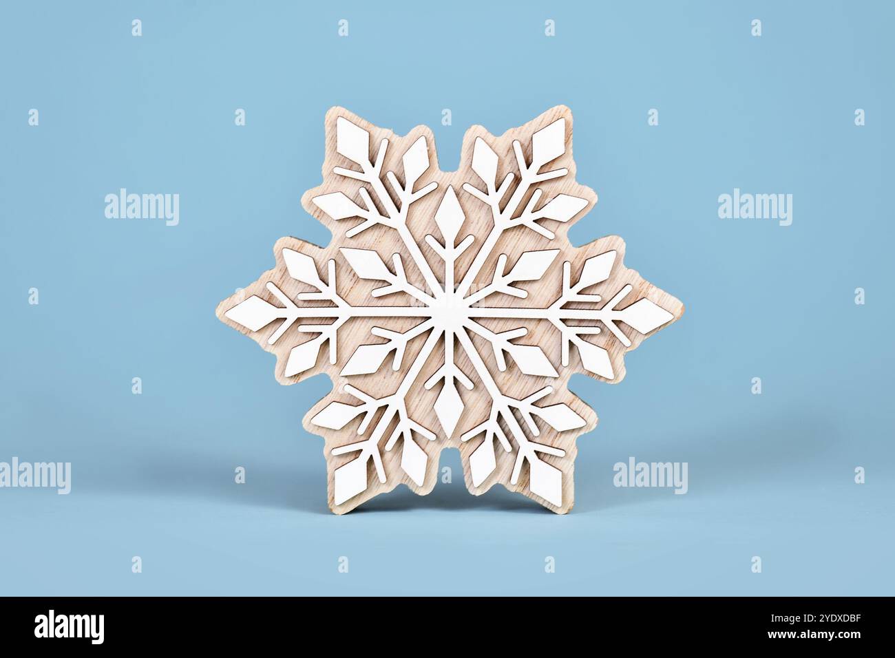 Single wooden and white winter snowflake ornament on light blue ...