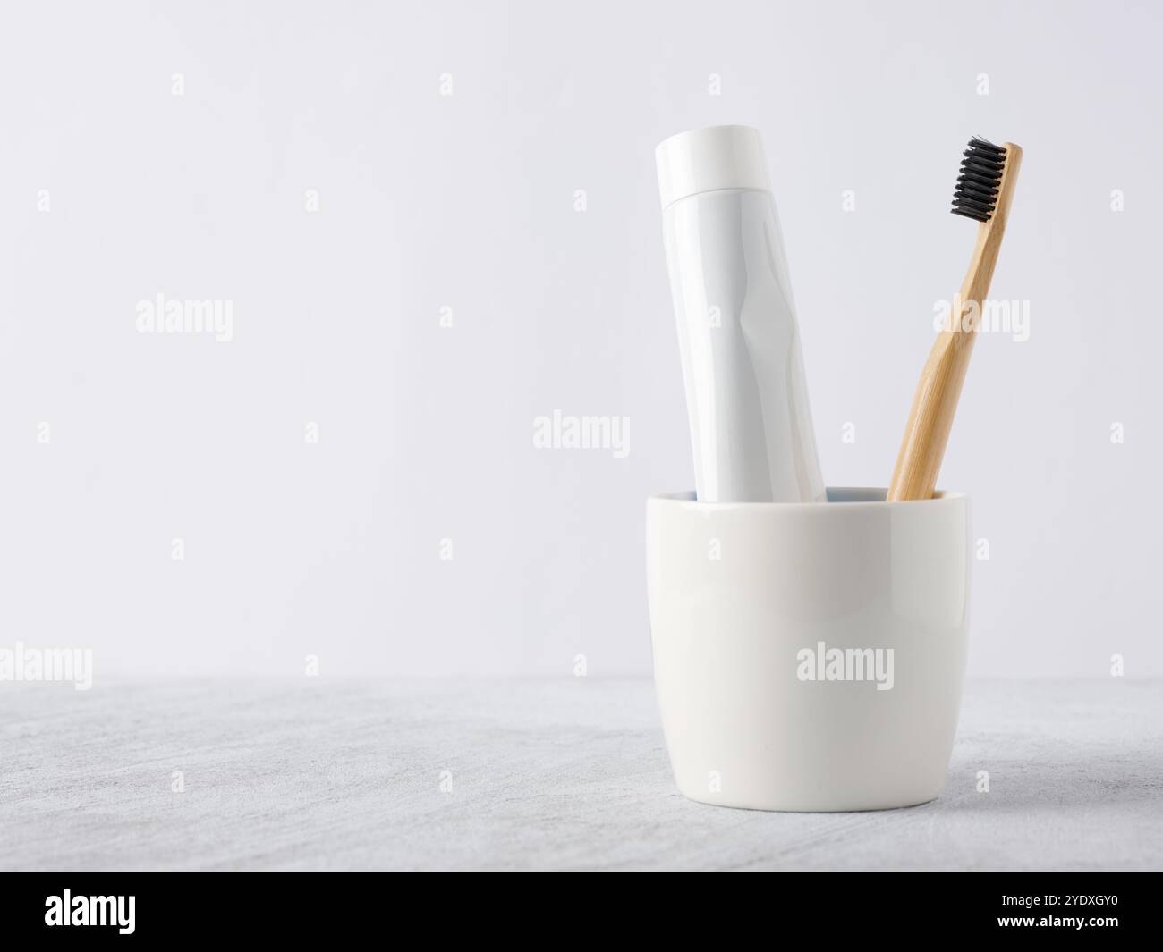 Bamboo toothbrush, white a cotton towel and a toothpaste in a white mug ...