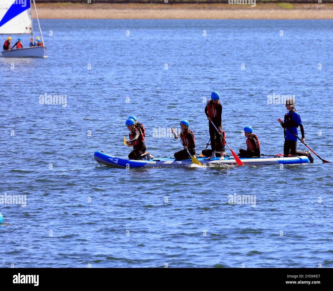 Paddle boarding and sailing lessons for young people in safety gear on ...