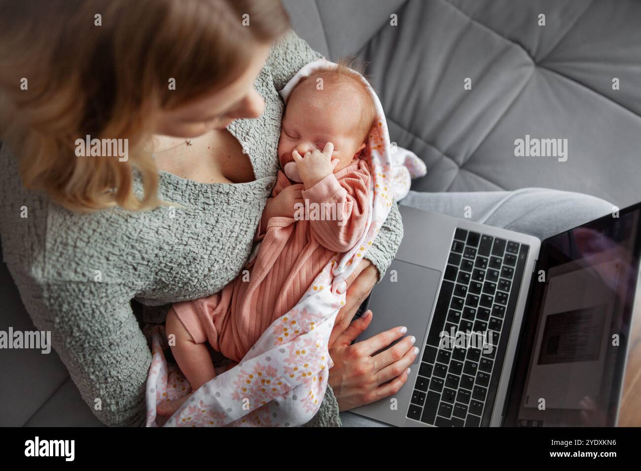 Working mother holding sleeping newborn baby in arms, multitasking with ...