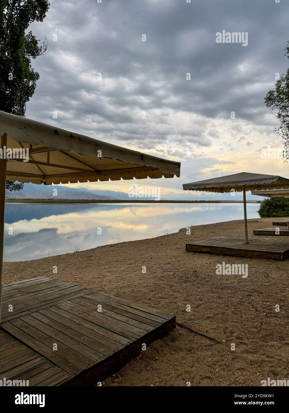 A beach with wooden platforms and canopies on the shore of Issyk-Kul ...