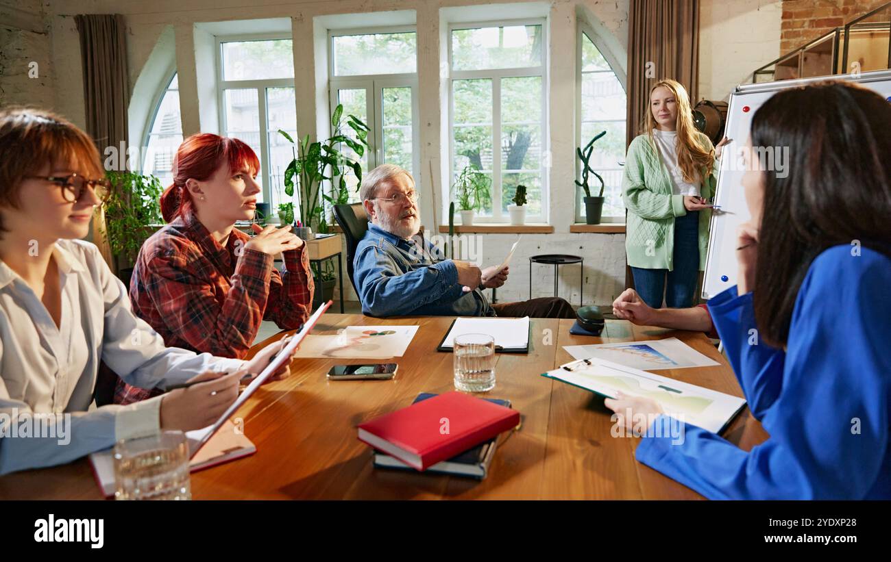 Group of business professionals carefully reviewing reports and data ...