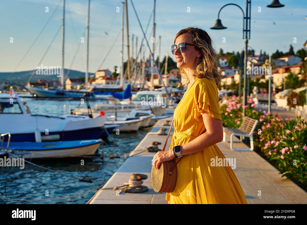 Woman is walking alone on sunny promenade with yacht in sea. Female ...