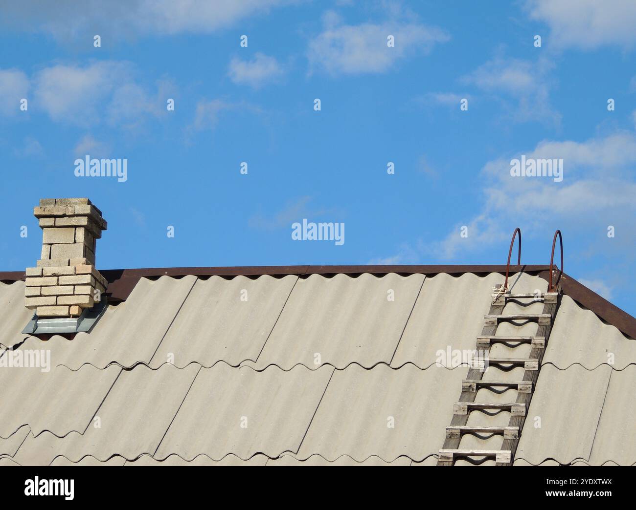 chimney brick pipe and wooden ladder on gray corrugated slate roof of ...