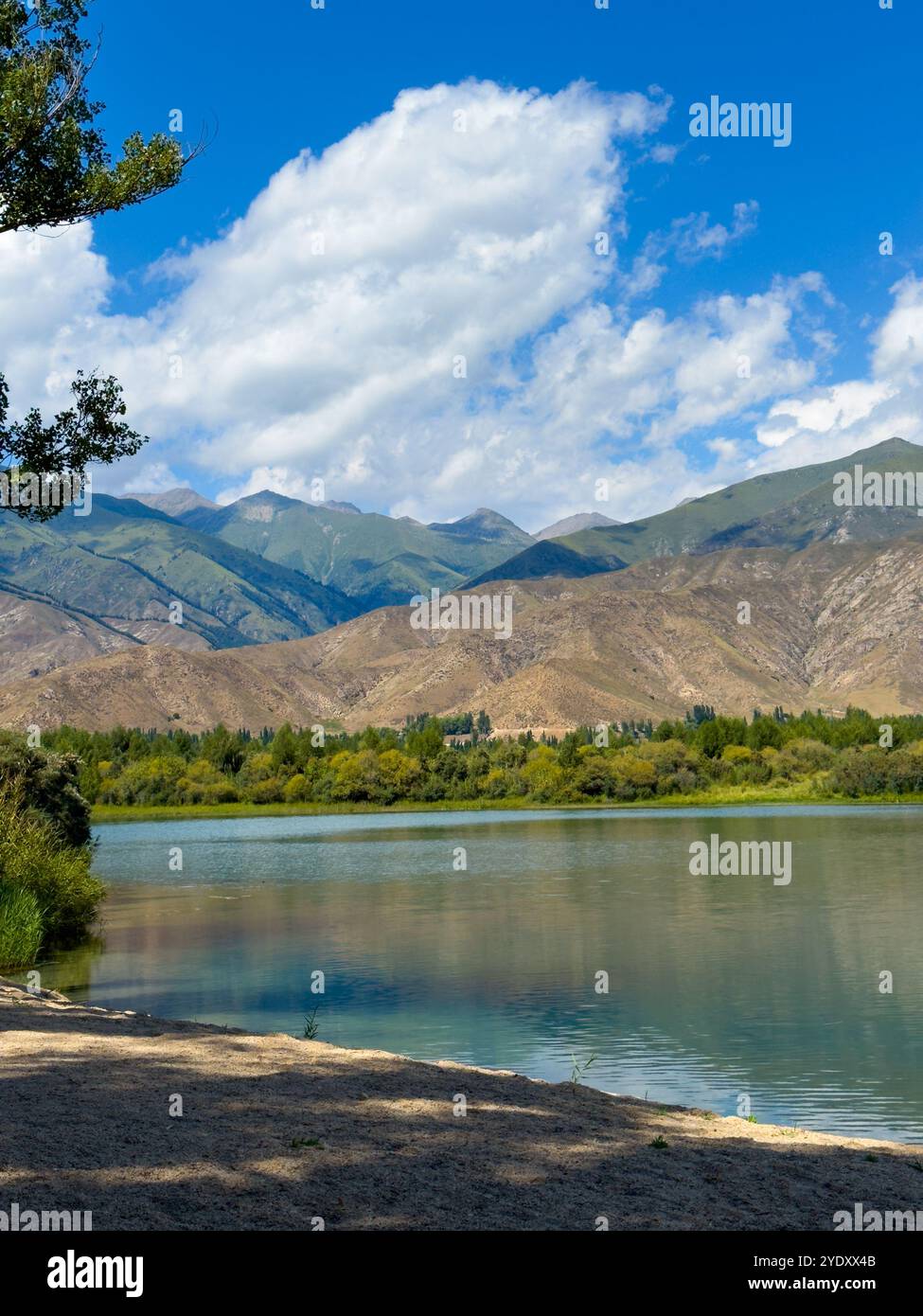 The calm water surface of Issyk-Kul lake with majestic mountains in the ...