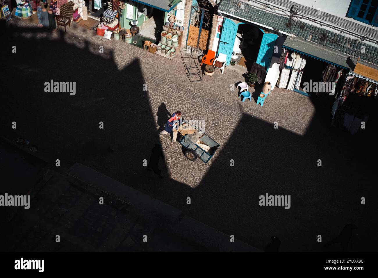 A birds eye view of a Moroccan street trader pushing a wooden handcart ...