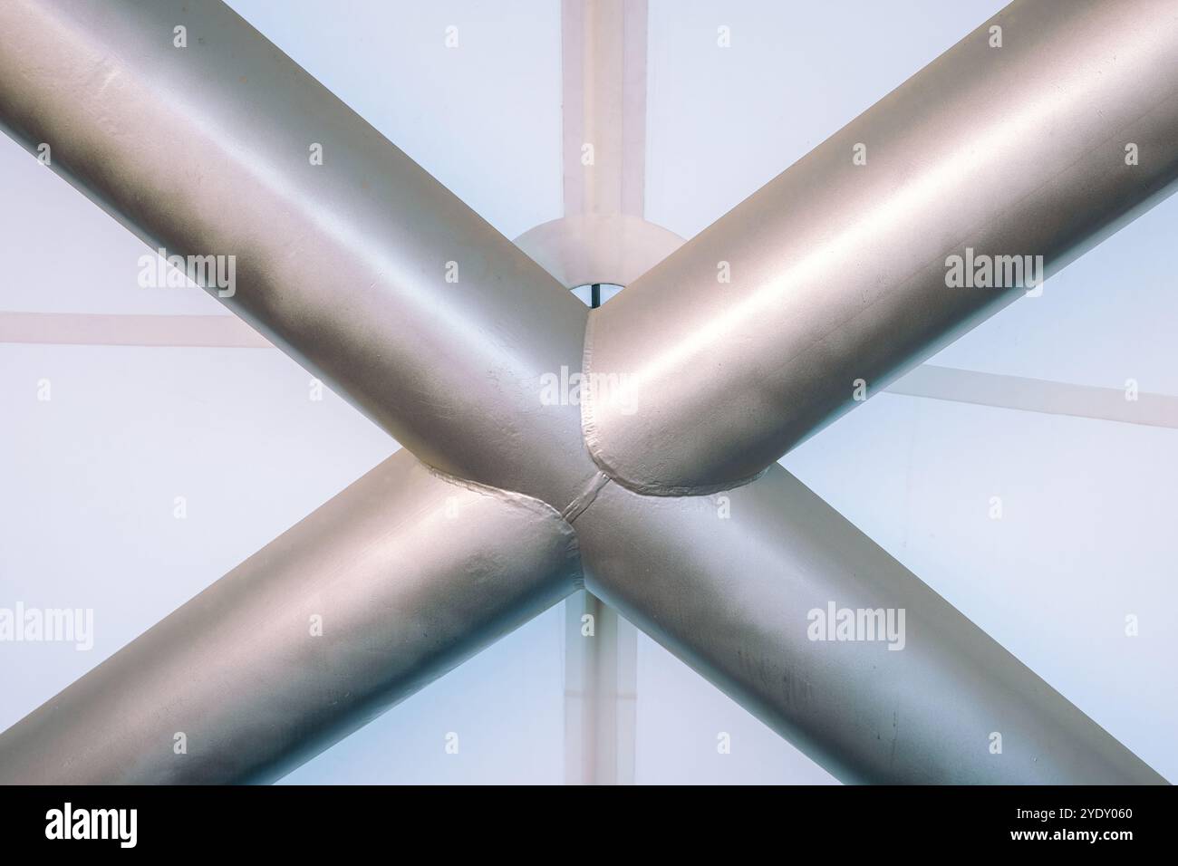Two metallic pipes intersect at a right angle, forming a striking ...