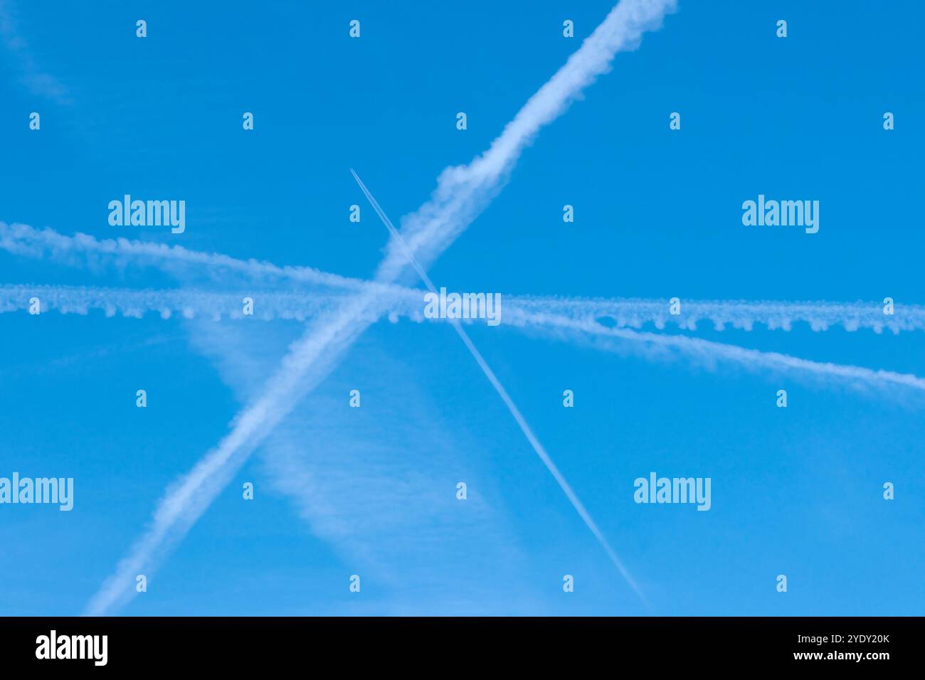 Vapour trails in blue sky from aircraft travel crossing and spreading ...