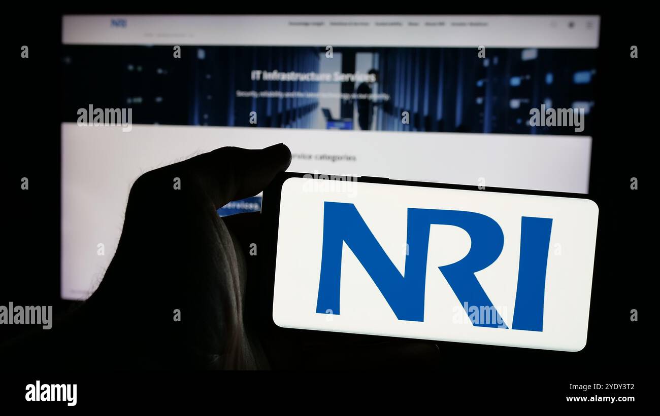 Person holding mobile phone with logo of company Nomura Research ...