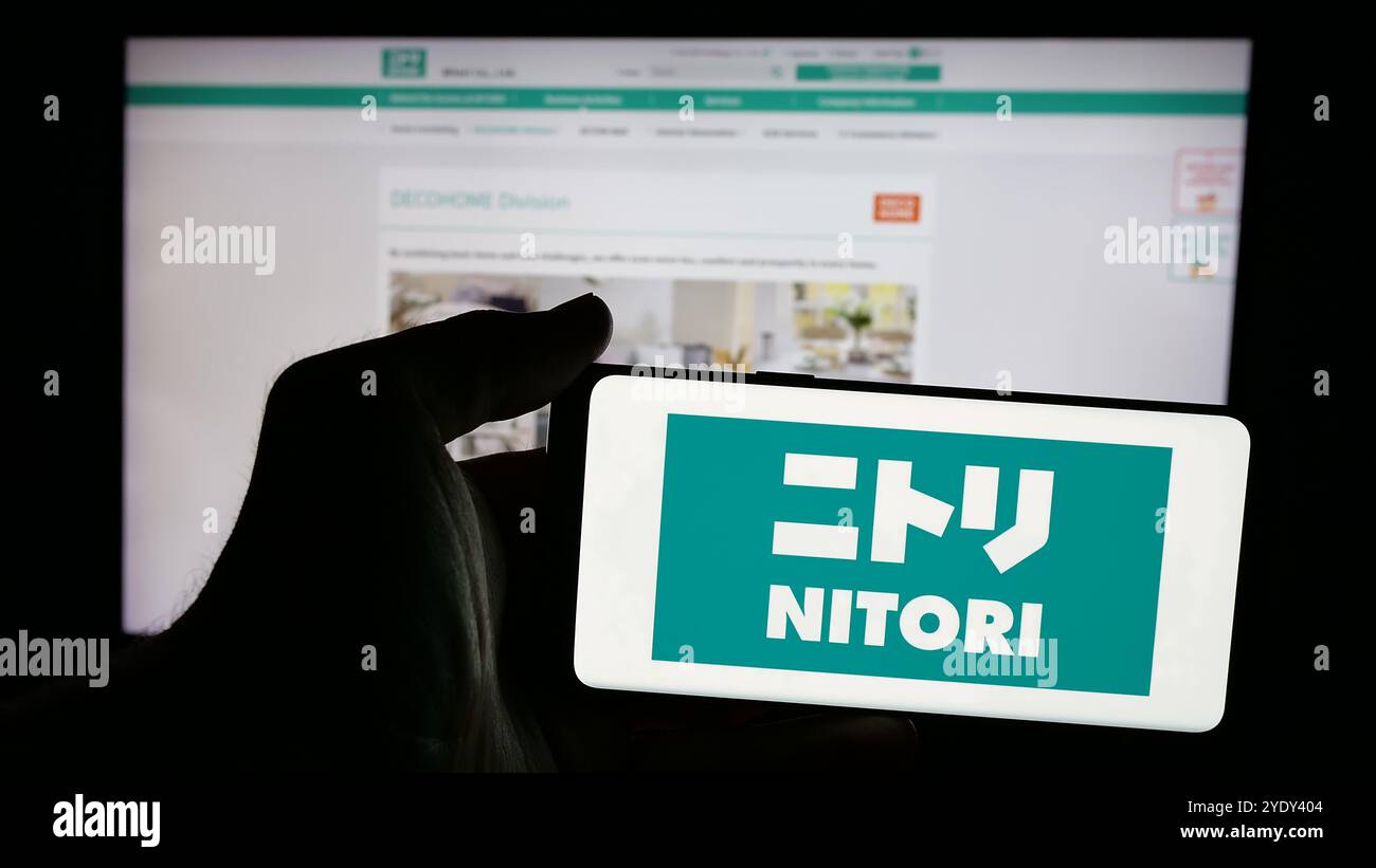 Person holding mobile phone with logo of Japanese retail company Nitori ...