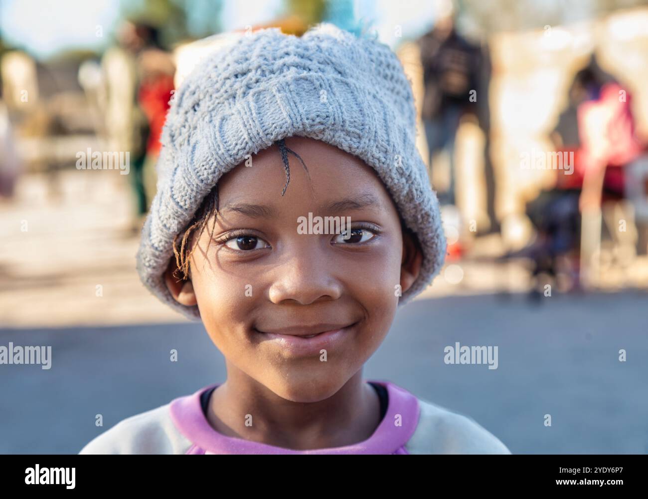 Portrait of a smiling village african girl standing in the dirt road ...