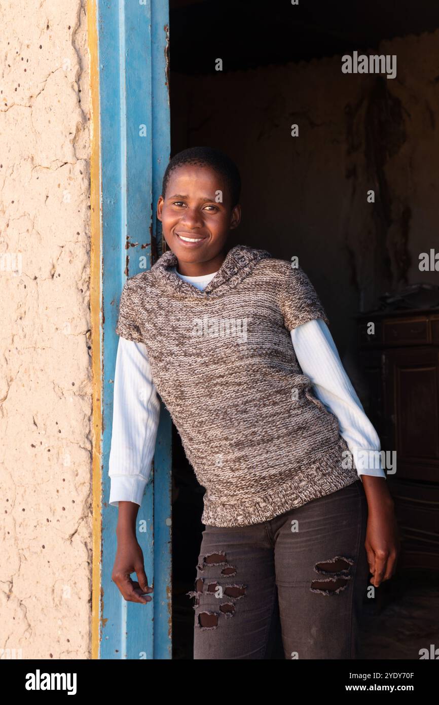 village african young woman standing in the door frame in front of her ...