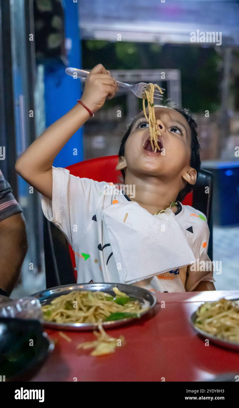 Child Eating Hakka Noodles Indoors at Night from Flat Angle Stock Photo ...
