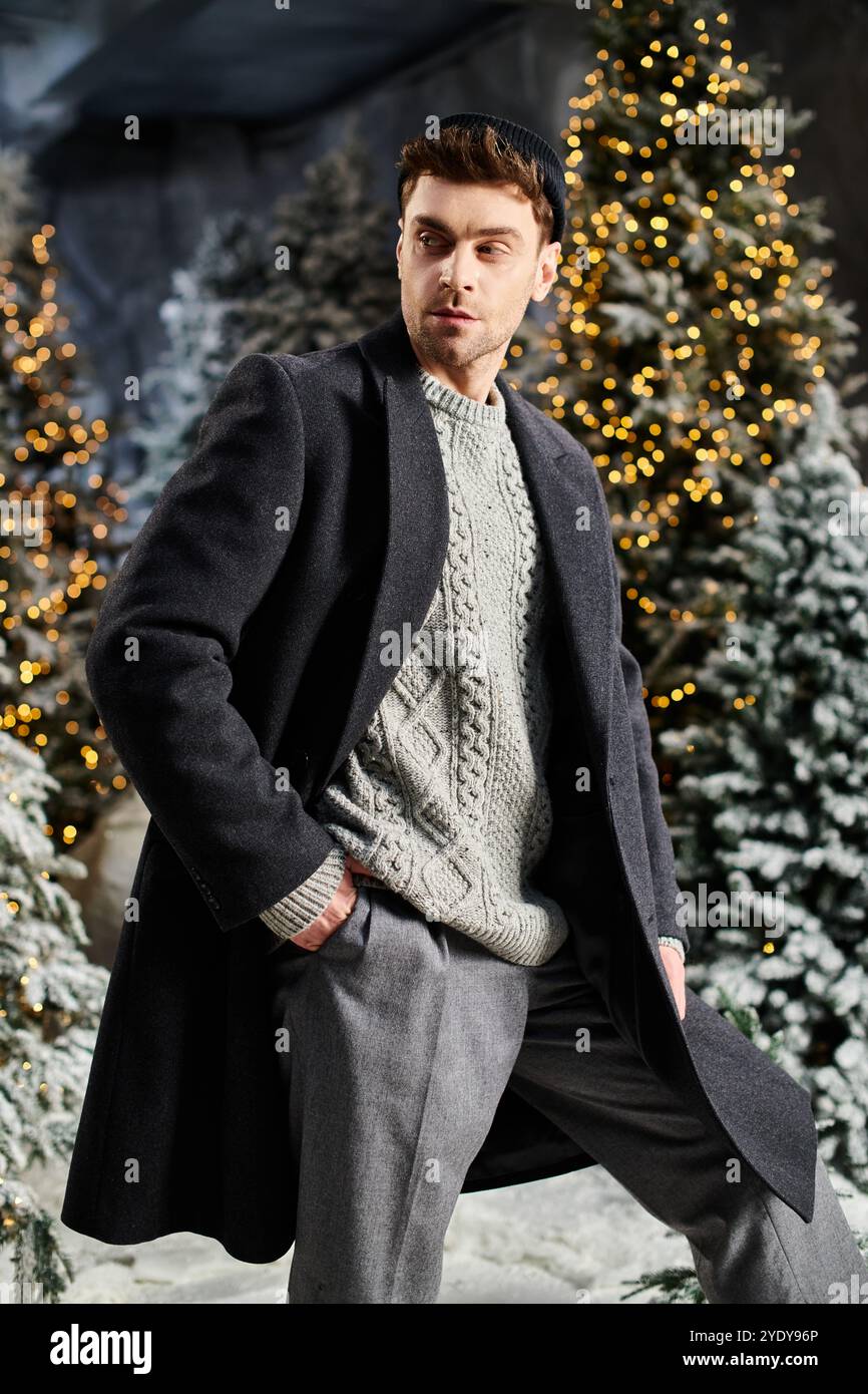 A handsome man dressed in winter attire stands confidently near snow ...