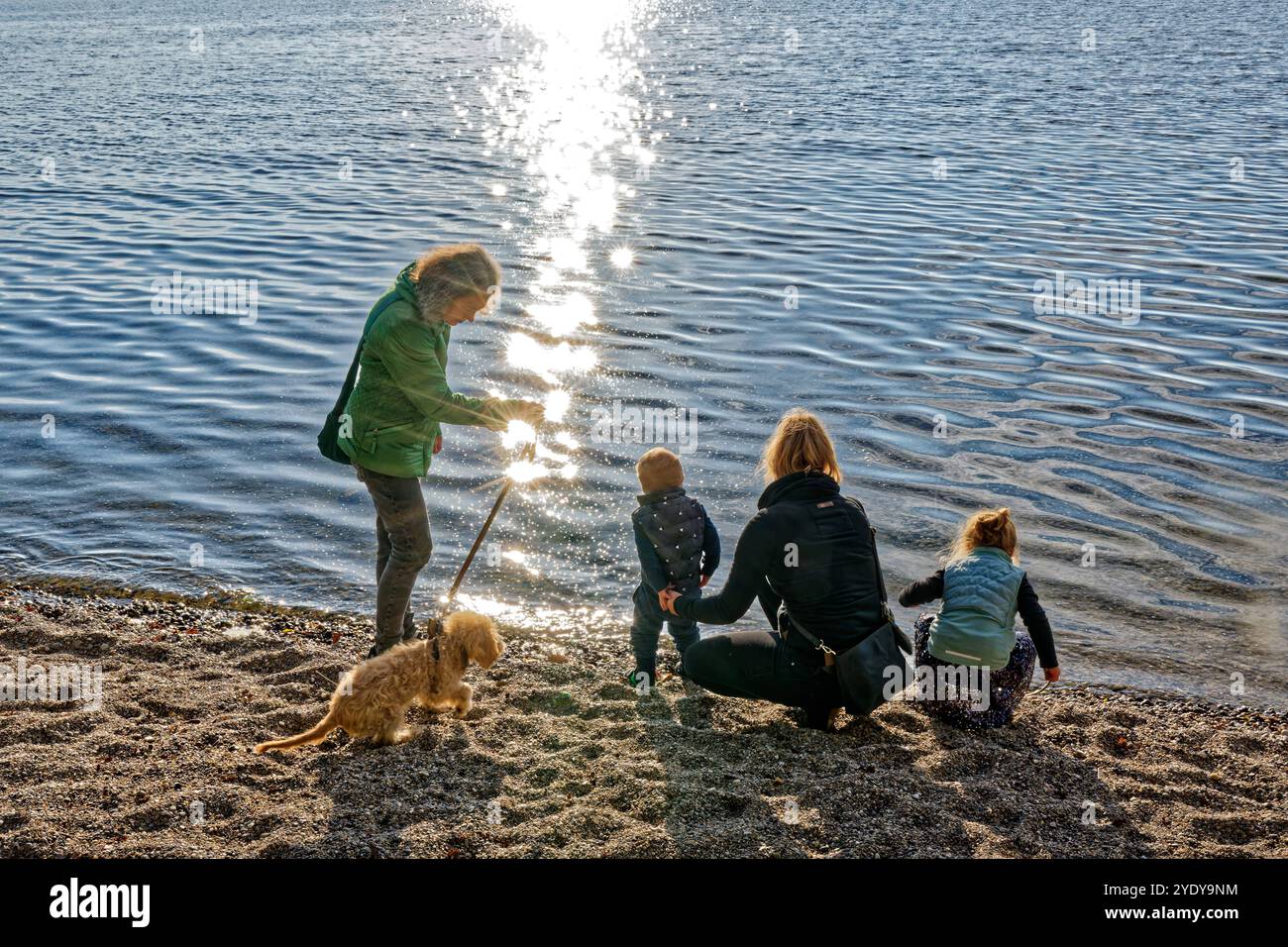 In der milden Herbstsonne. Die junge Familie mit Oma und Hund am See ...