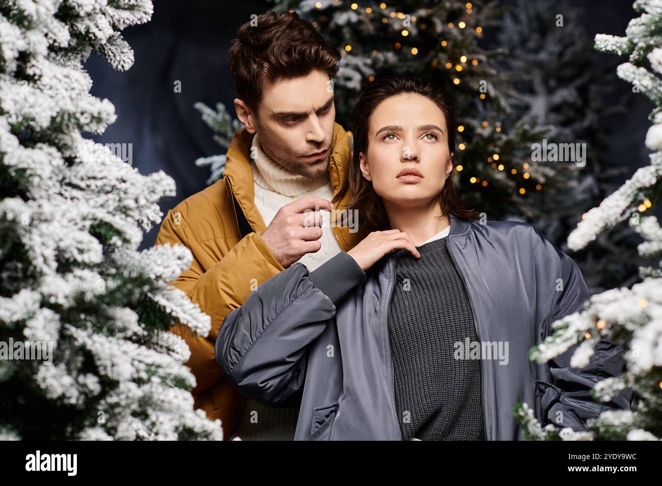 A romantic couple clad in winter jackets enjoys a festive moment ...
