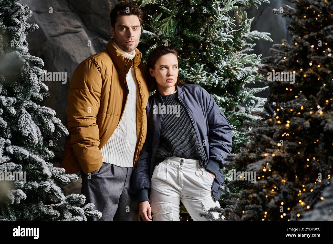 A stylish couple enjoys the wintry ambiance among snow-dusted pine ...