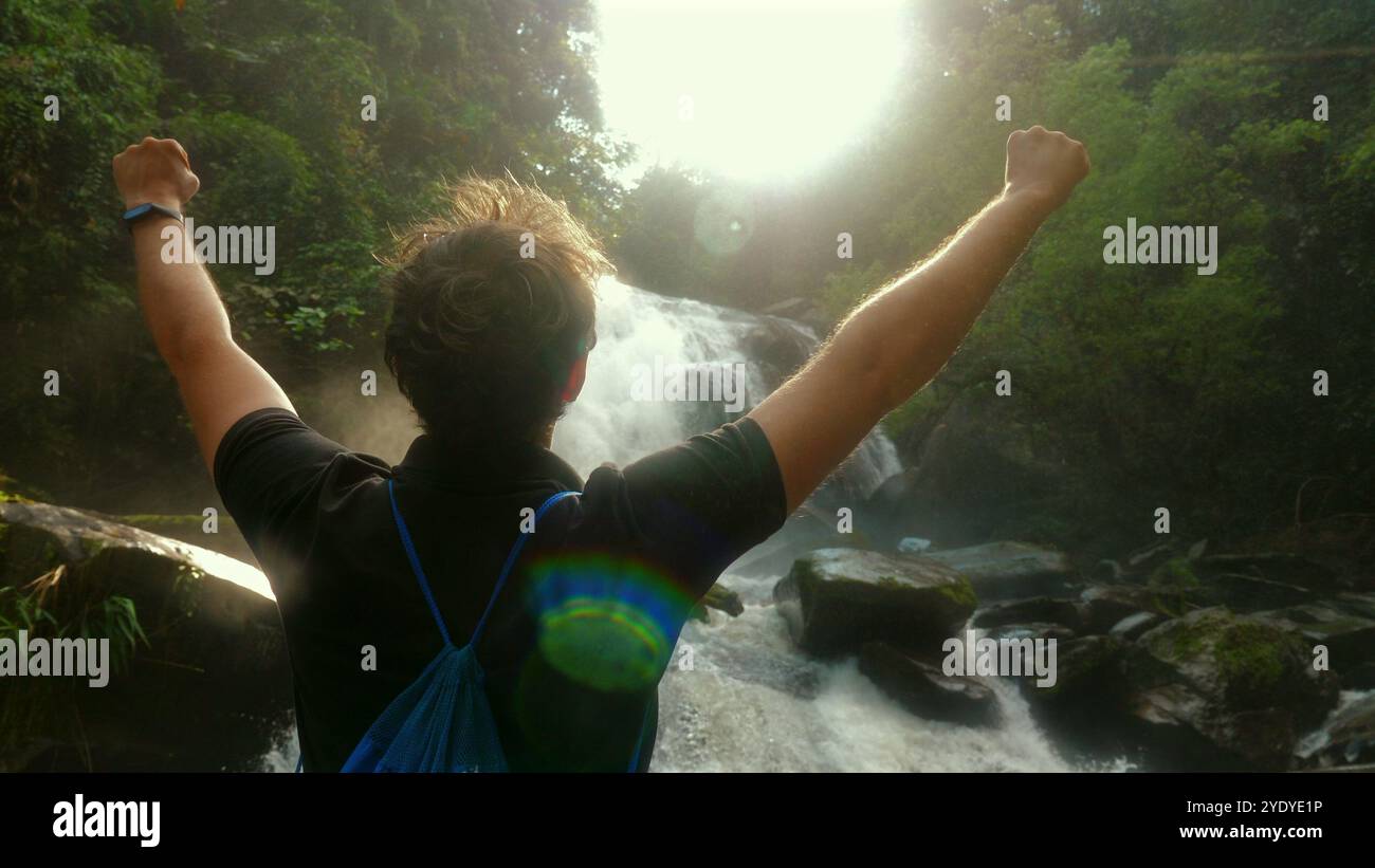 Person Raising Arms in Triumph at Waterfall, Celebrating Achievement ...