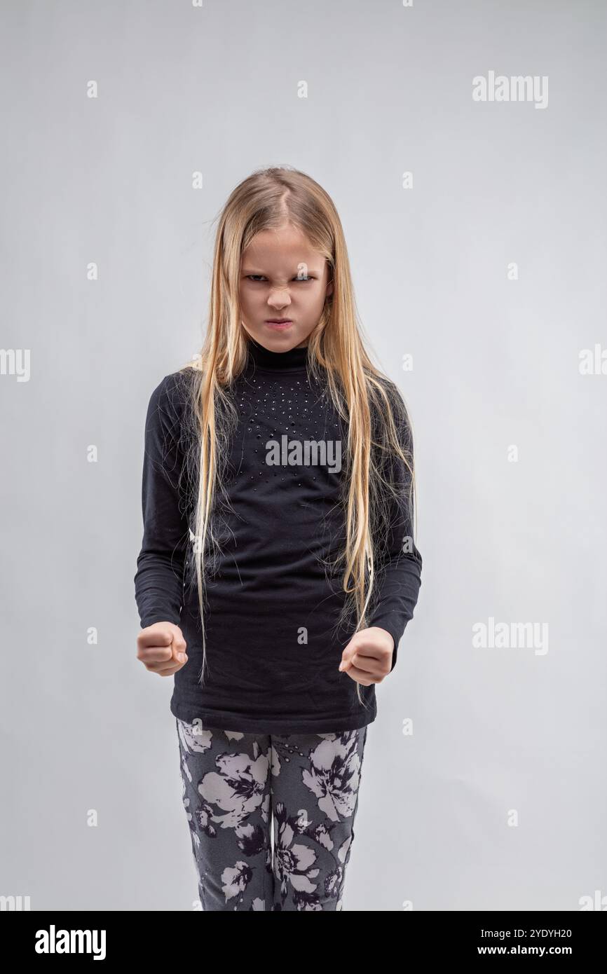 Portrait of a blonde girl clenching her fists, expressing anger and ...