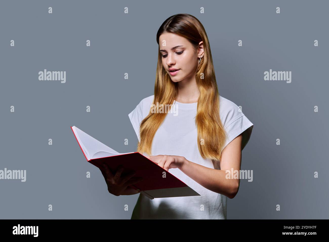 Portrait of teenager student girl holding notebook on gray studio ...