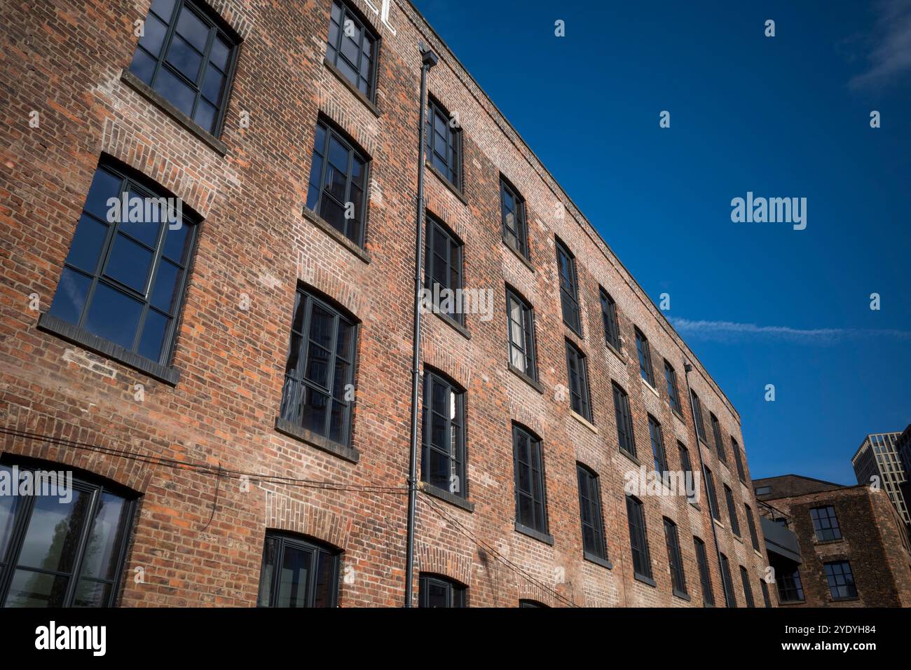 Historic brick mill building converted to apartments, against a clear ...