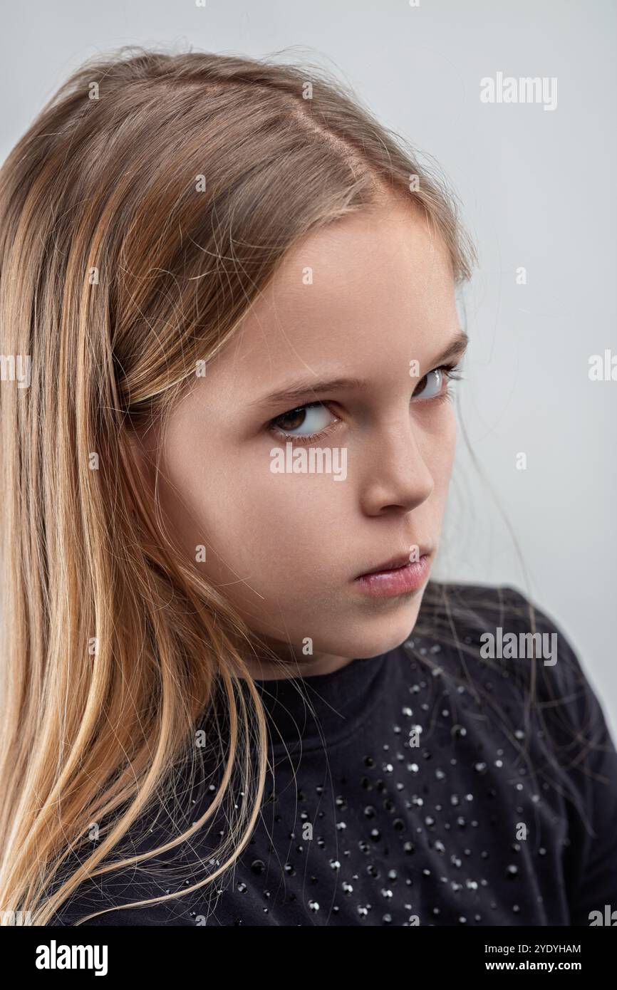 Young girl with long blond hair and black shirt shows intense emotions ...
