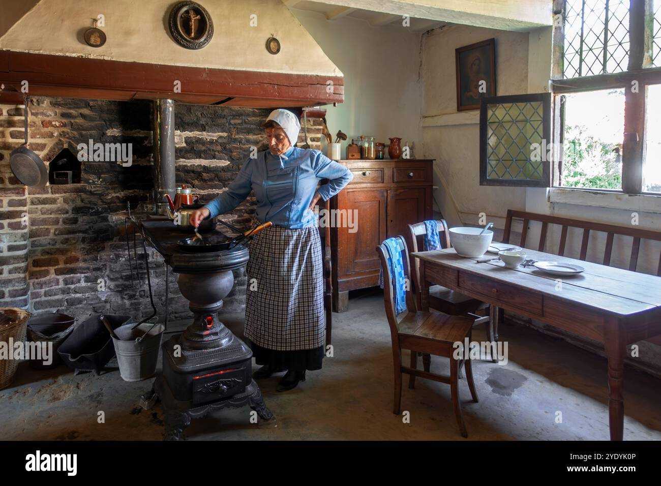 Old woman cooking on antique Flemish cast-iron coal stove / Leuvense ...